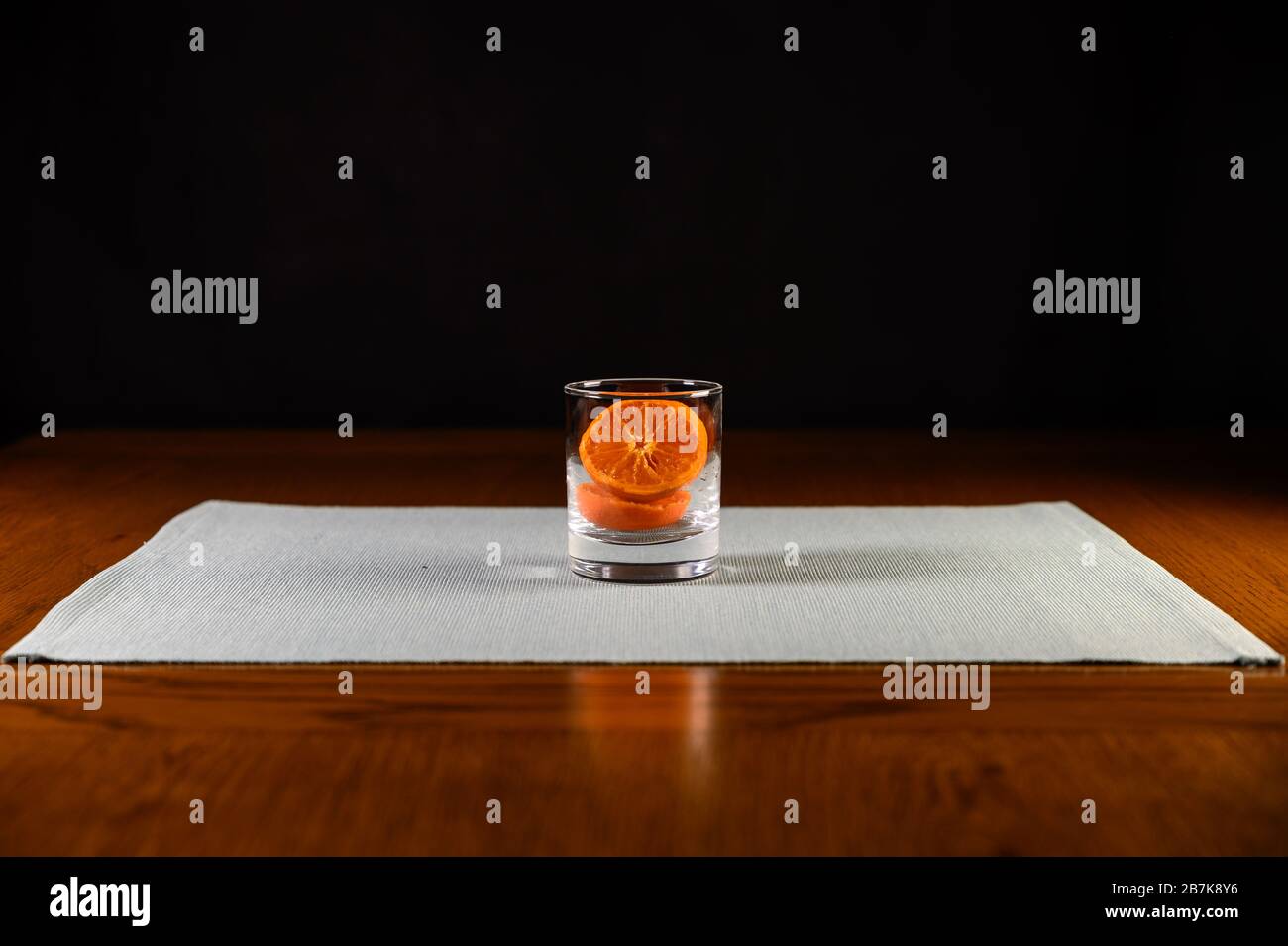 Isolated glass with sliced oranges inside on green mat ,black ...