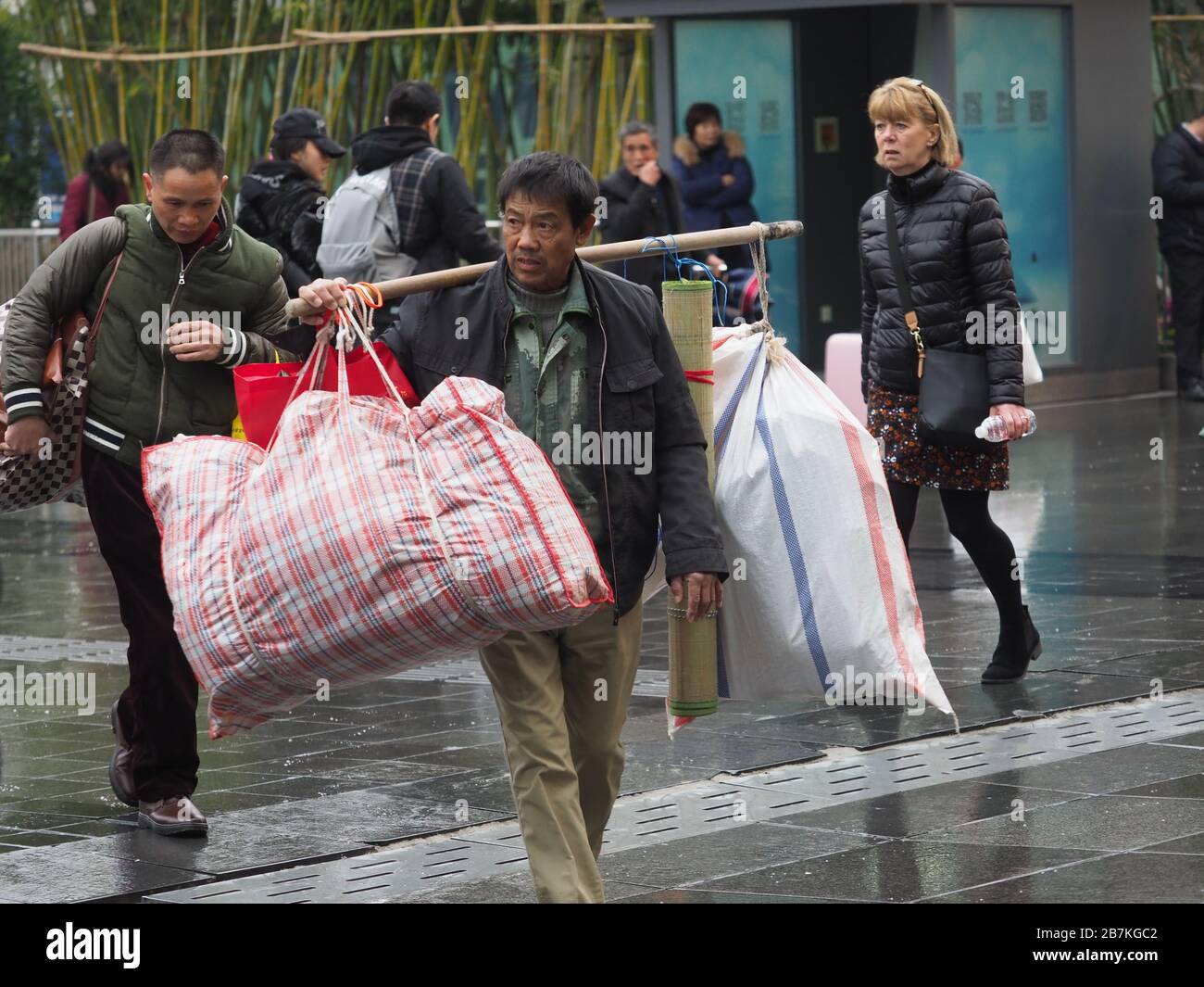 --File--A migrant worker carries luggages with a shoulder pole at the ...