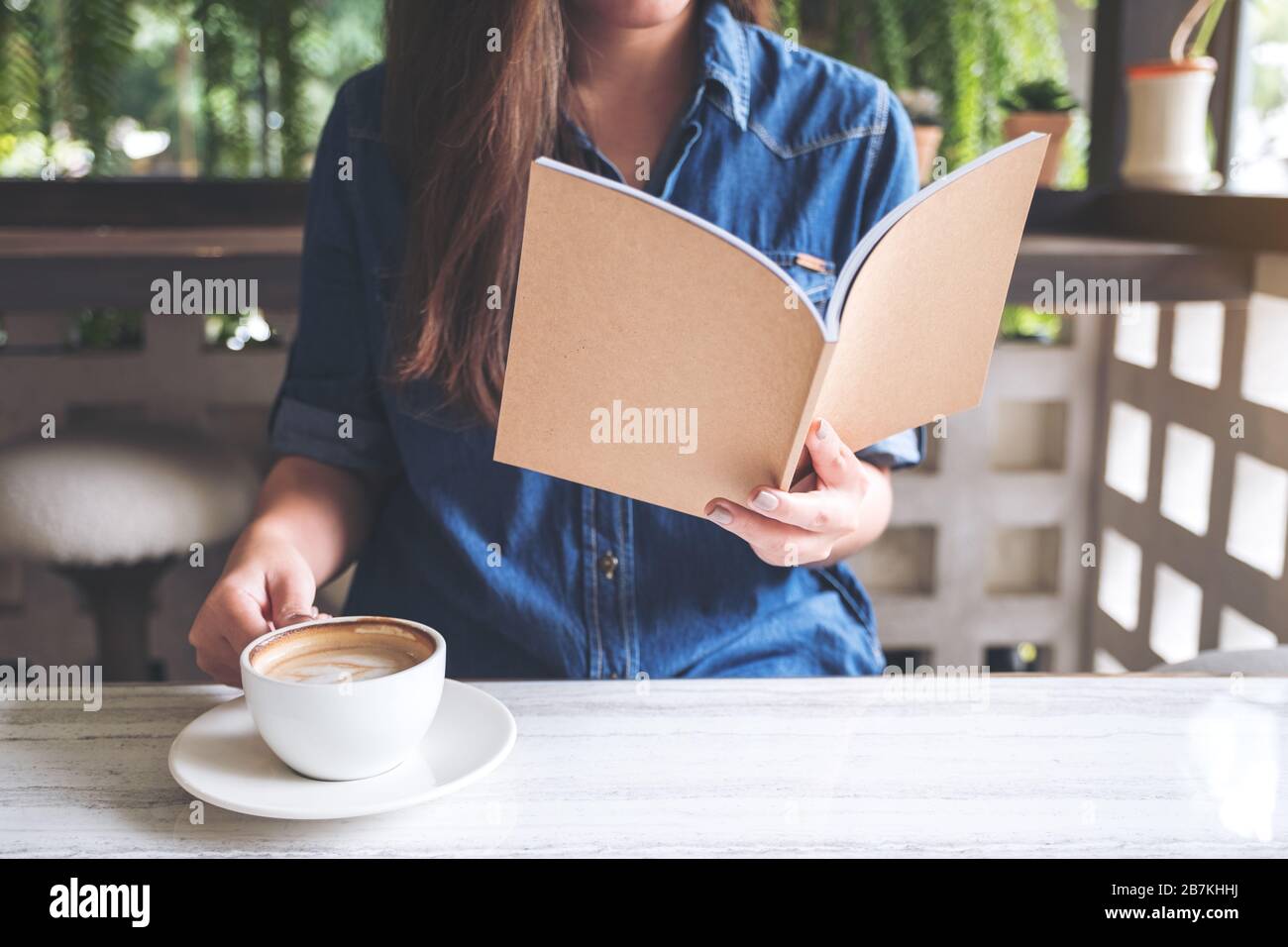 Closeup image of an asian woman reading a book while drinking coffee in ...