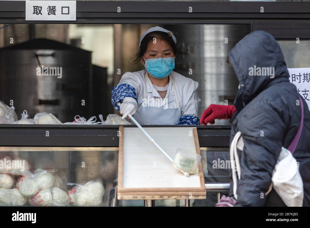 A staff of a steamed bun shop delivers buns to customers using a wooden ...