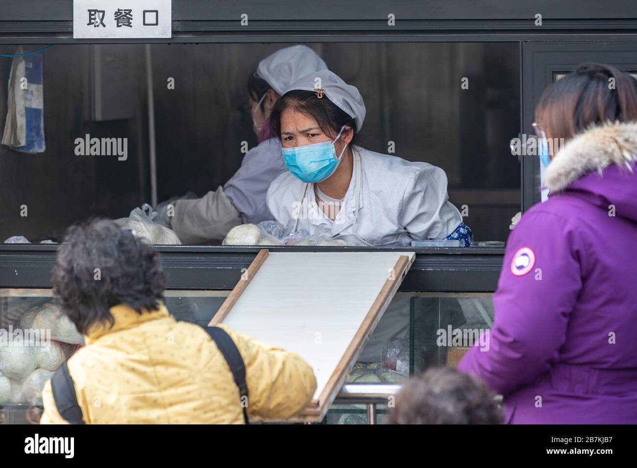 A staff of a steamed bun shop delivers buns to customers using a wooden ...