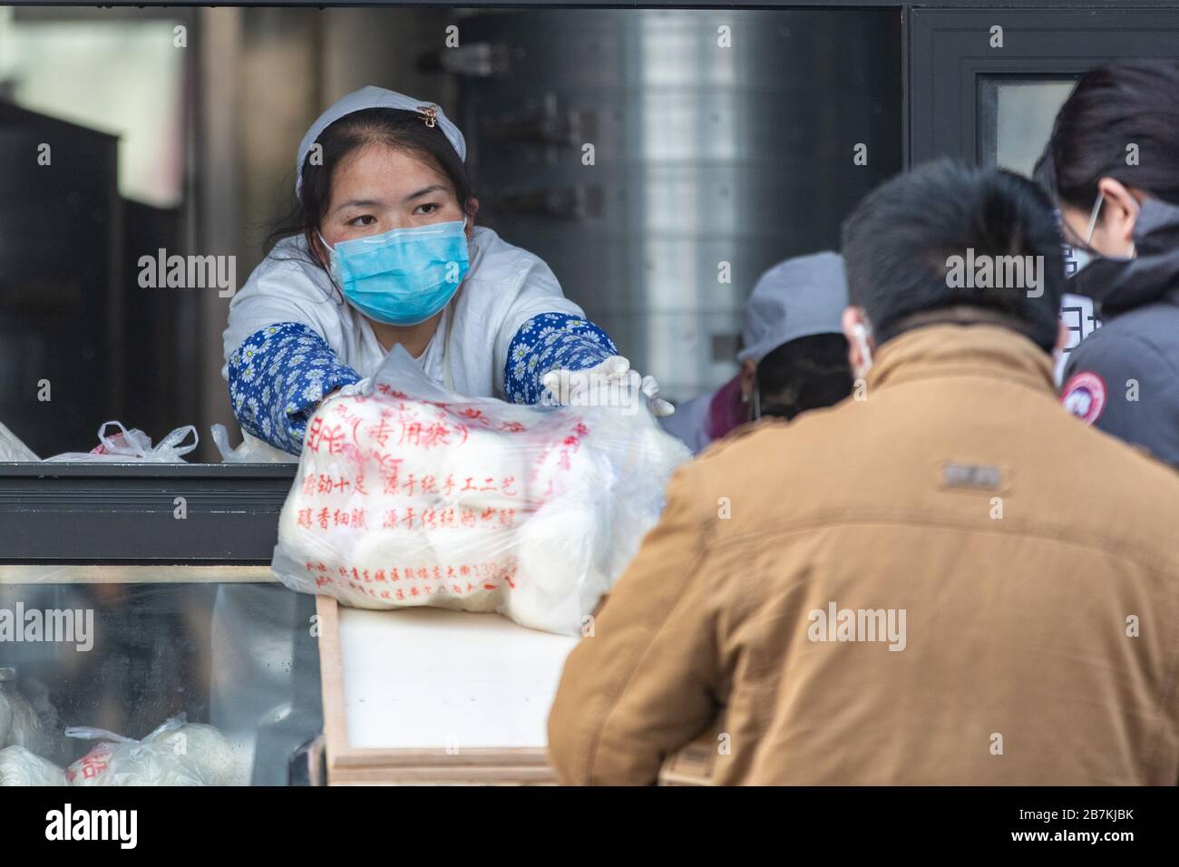 A staff of a steamed bun shop delivers buns to customers using a wooden ...