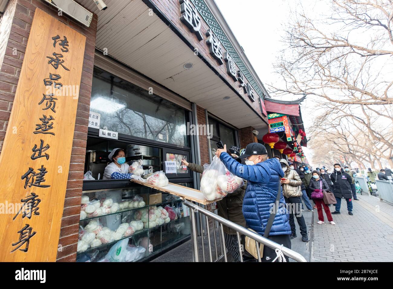 A staff of a steamed bun shop delivers buns to customers using a wooden ...