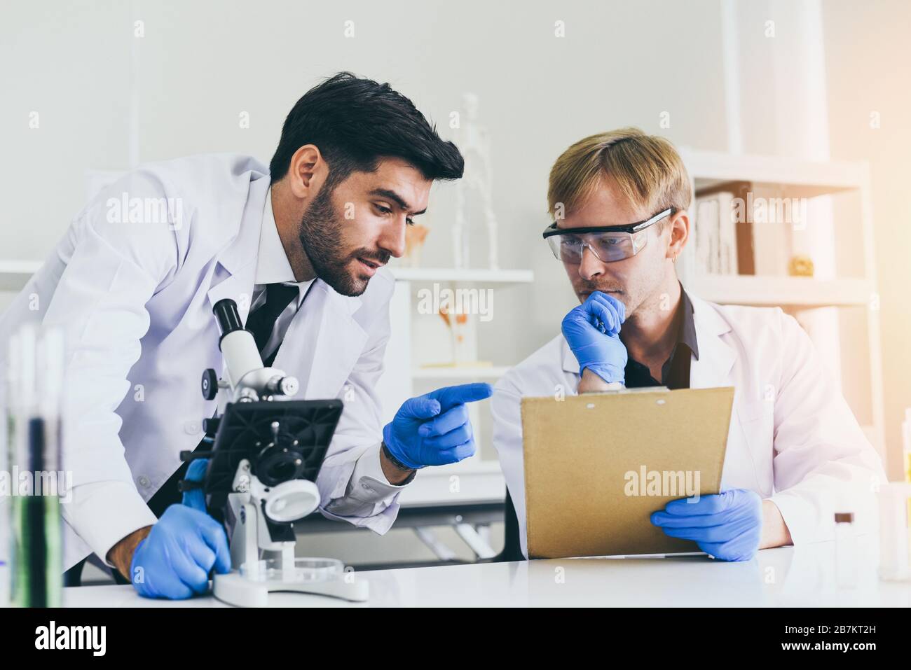 Team of scientist research working together conduct experiments and looks on microscope in ...