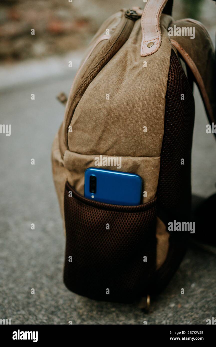 Blue smartphone tucked in the side pocket of a brown functional camera ...