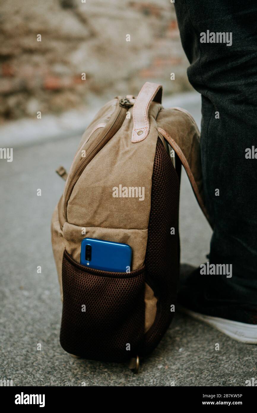 Blue smartphone tucked in the side pocket of a brown functional camera ...