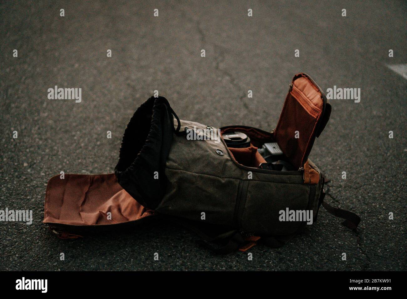 Fully open gray canvas camera utility backpack laid on the ground with ...