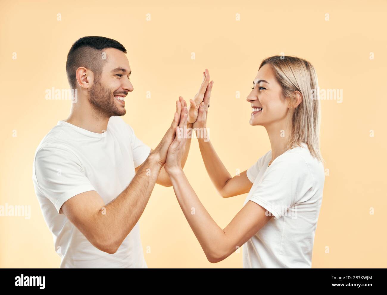 Portrait of young smiling couple giving high five to each other over ...
