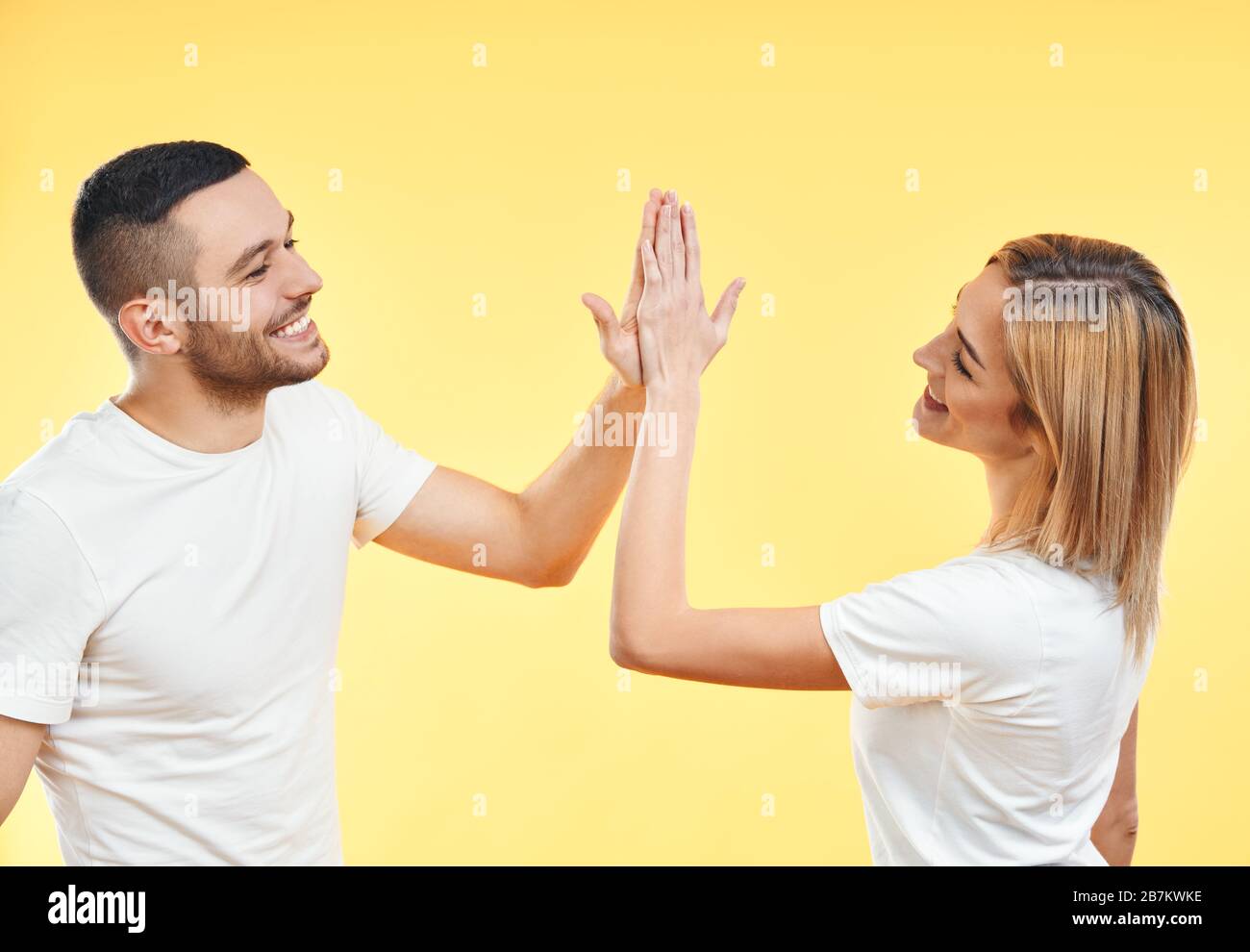 Portrait of young smiling couple giving high five to each other over ...