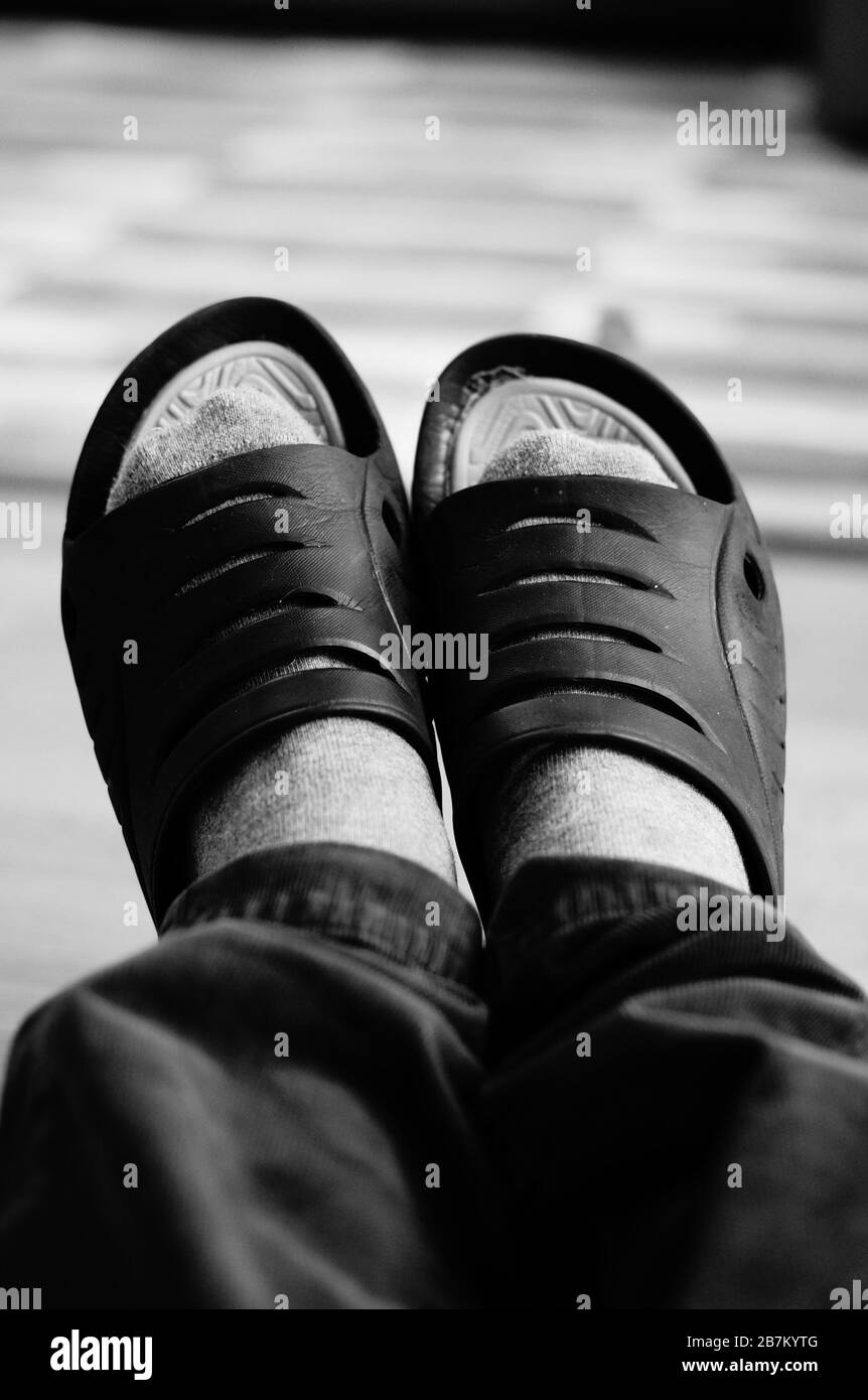 Vertical high angle greyscale closeup shot of human feet in black ...