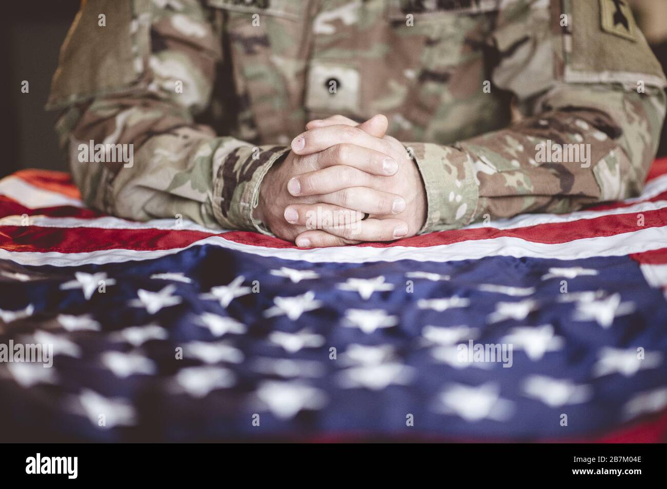 American soldier mourning and praying with the American flag in front ...