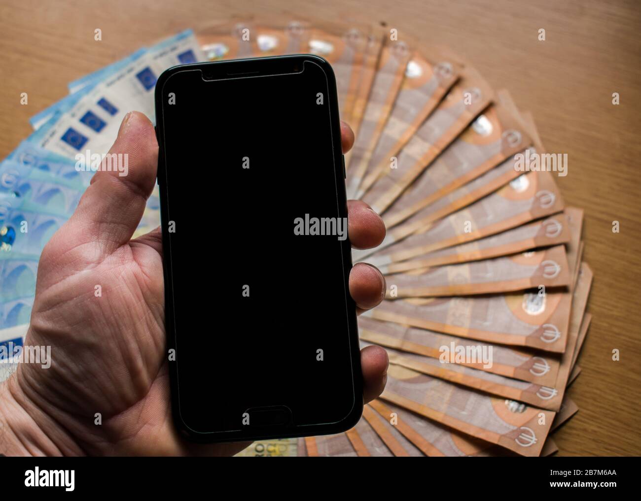 Human, man hand holding smartphone. European currency, money background ...