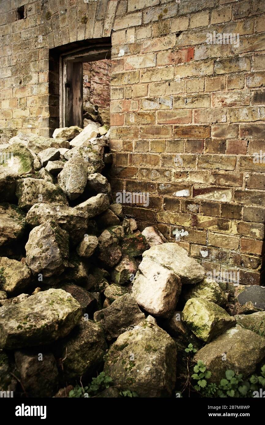 Rocks spilling out of broken window in old derelict brick building ...