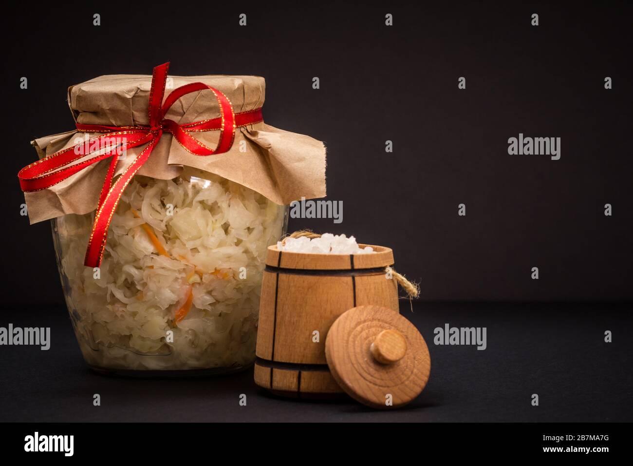 Homemade fermented cabbage in glass jar and small wooden barrel with ...