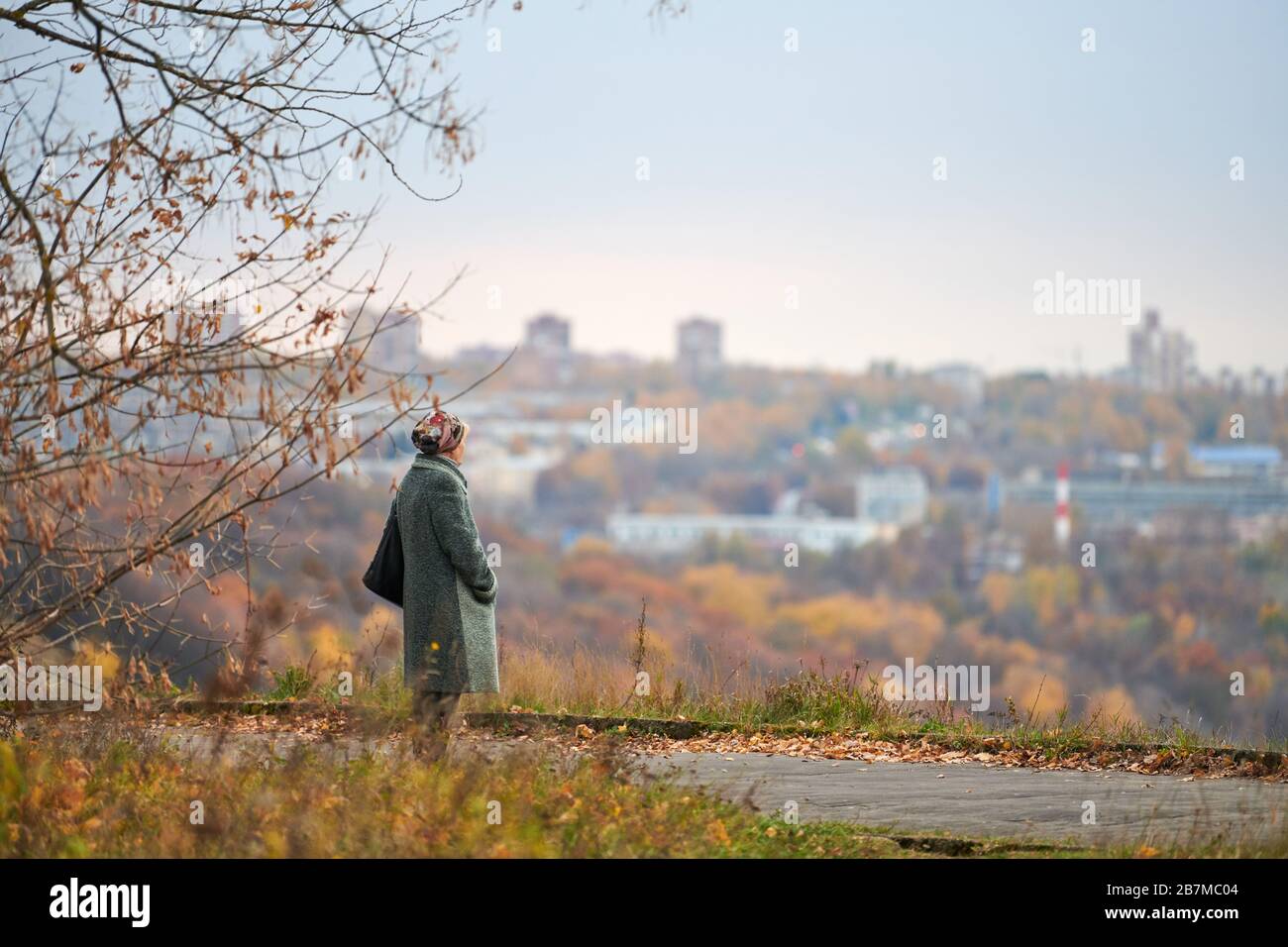 Old widow walking in autumn city park. Lonely woman looking deep at ...