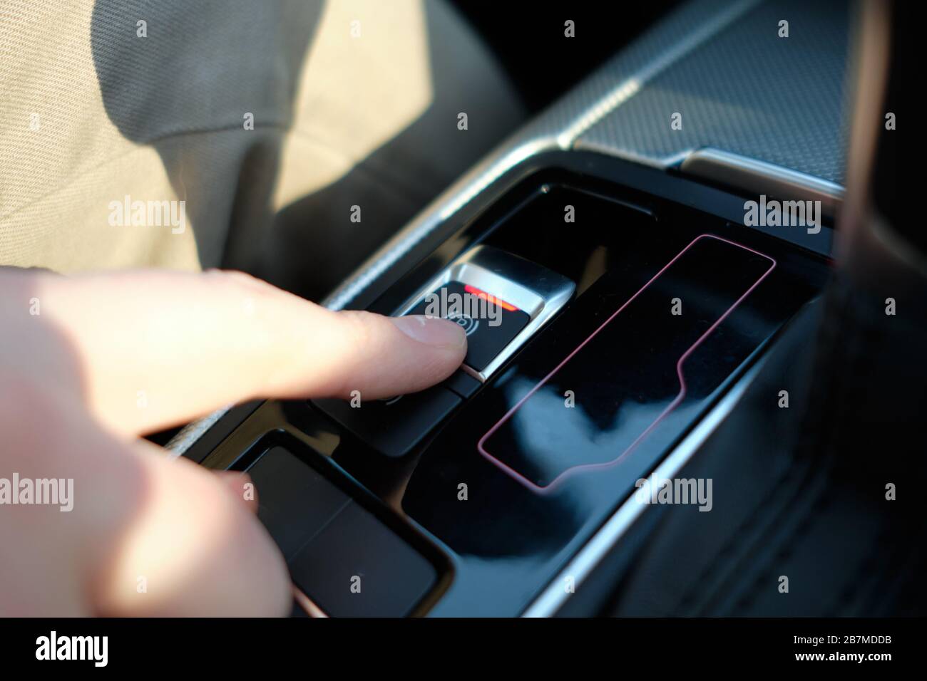 A man in a modern car. Hand presses the auto parking button. Close up ...