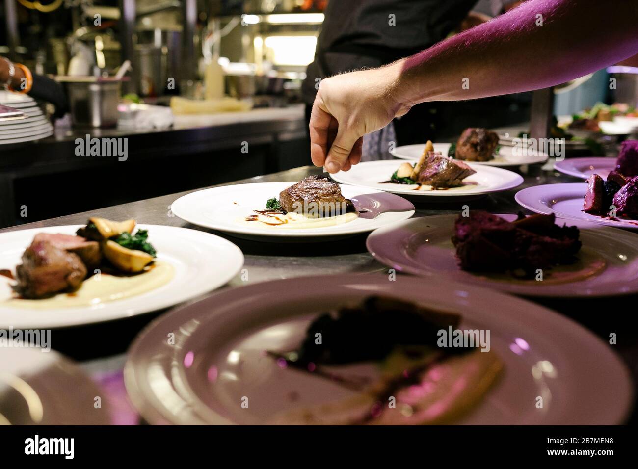 Chef adding salt on a top of a piece of meat during it's preparation ...
