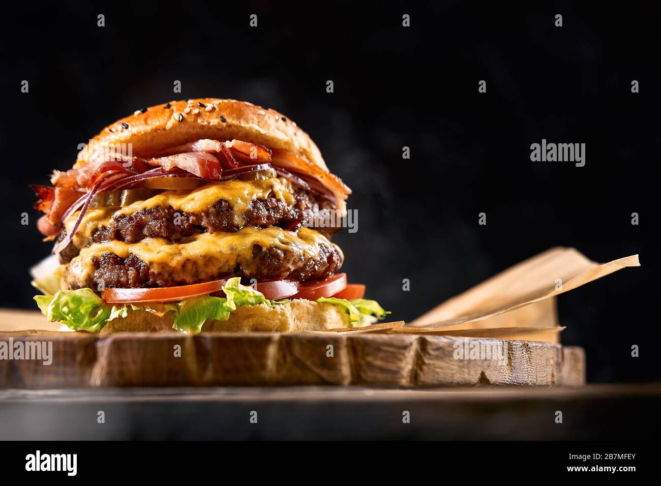 Juicy burger on the board, black background. Dark background, fast food ...