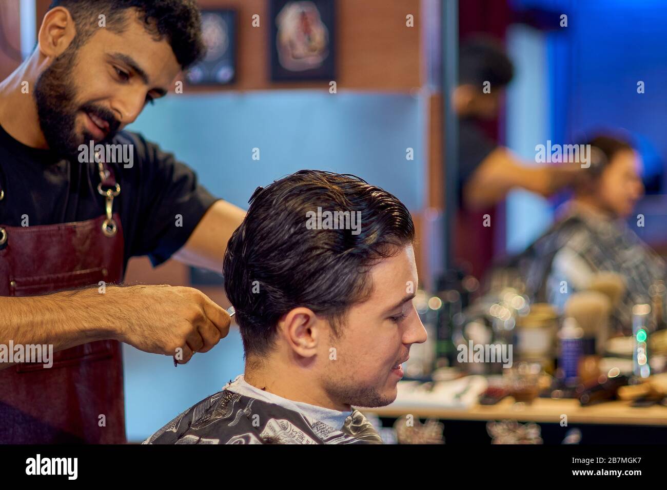 Master cuts hair and beard of men in the barbershop, hairdresser makes ...