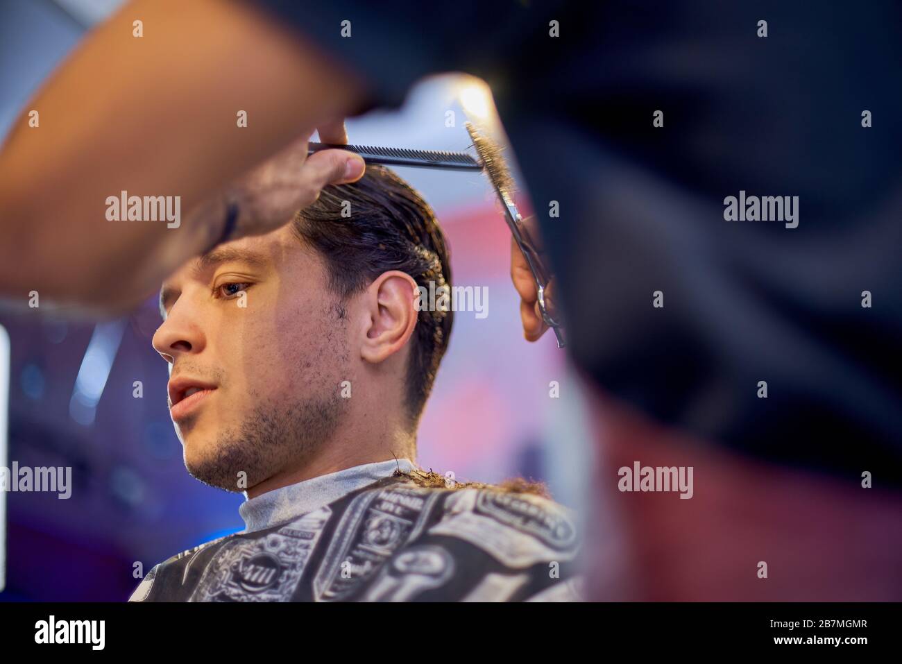 Master cuts hair and beard of men in the barbershop, hairdresser makes ...