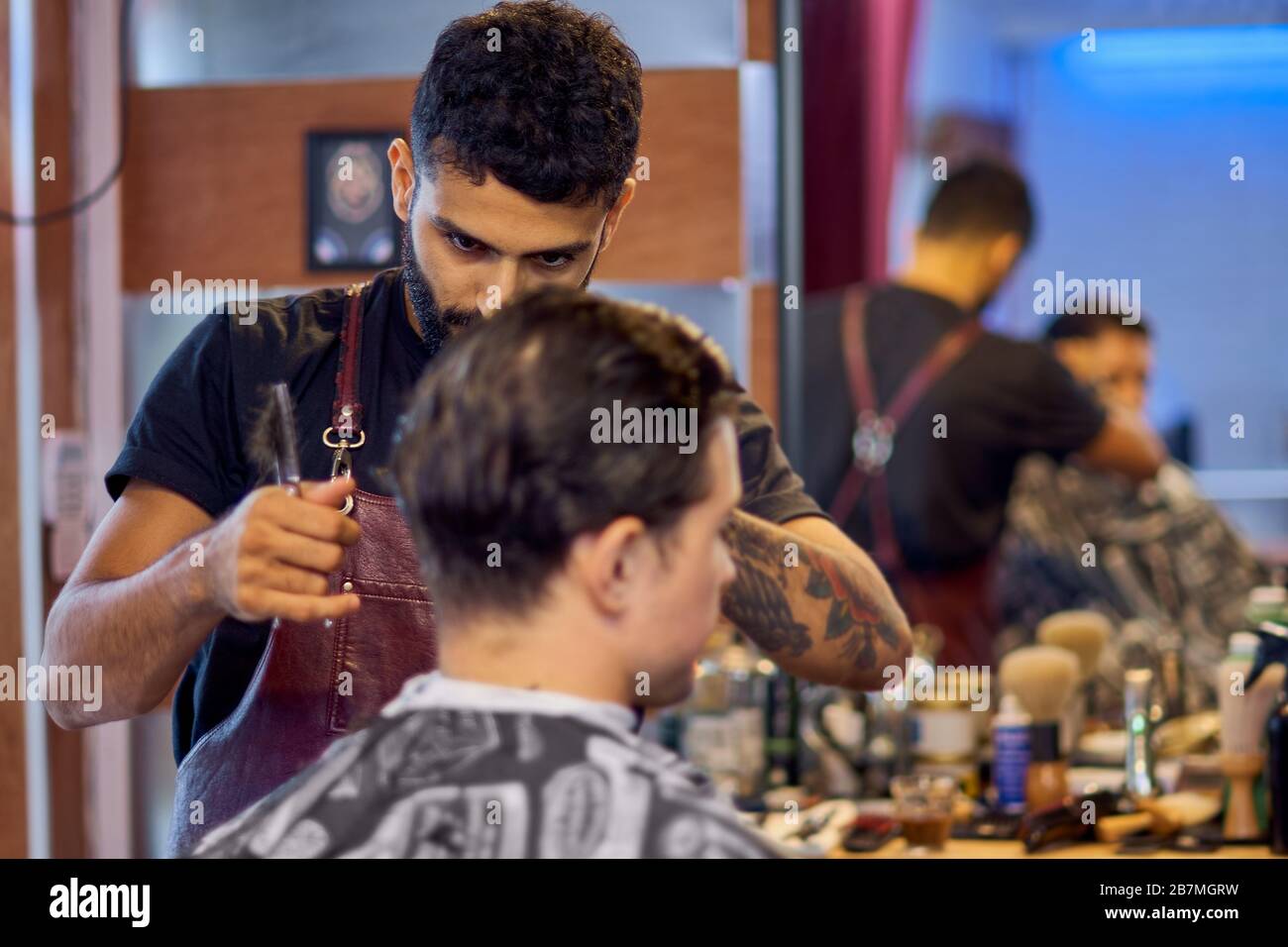 Master cuts hair and beard of men in the barbershop, hairdresser makes ...