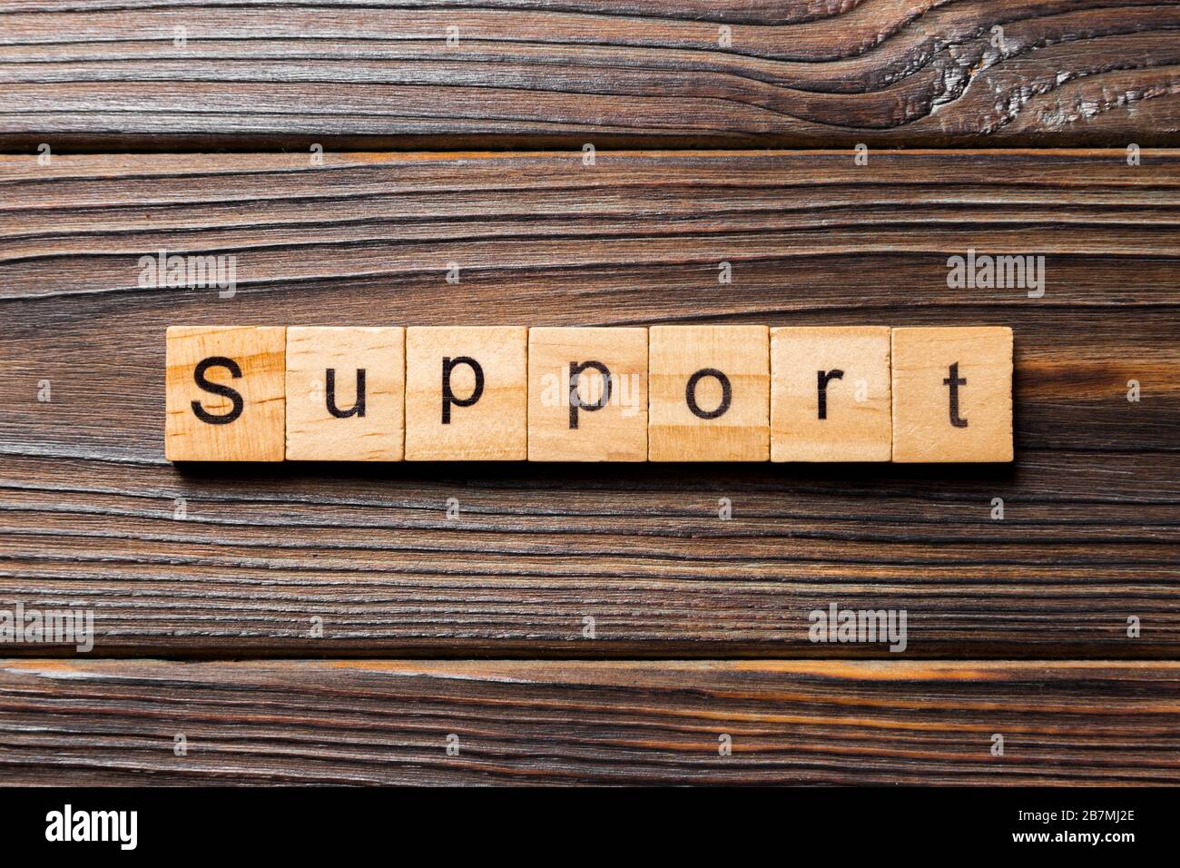 Support word written on wood block. Support text on wooden table for ...
