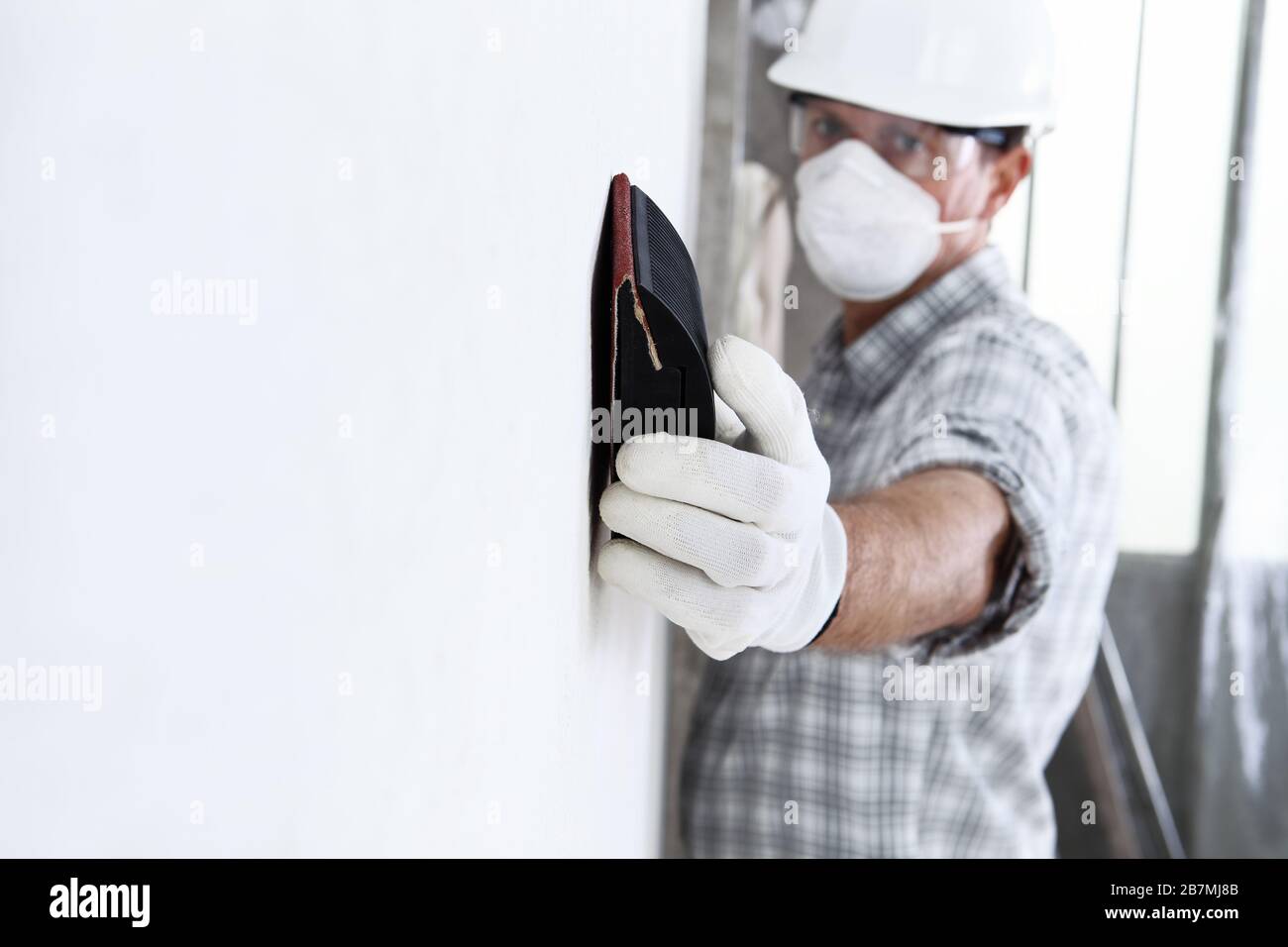 man sand the wall with sandpaper, professional construction worker with ...