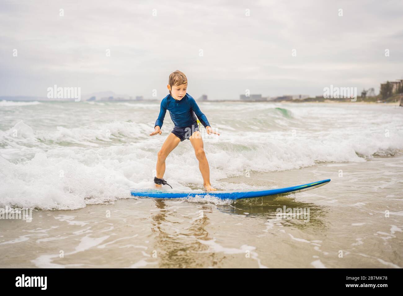 Healthy young boy learning to surf in the sea or ocean Stock Photo - Alamy