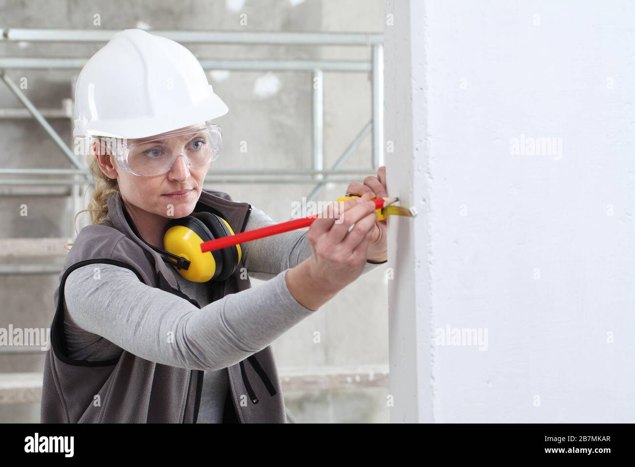 woman construction worker work with meter tape and pencil, measure wall ...