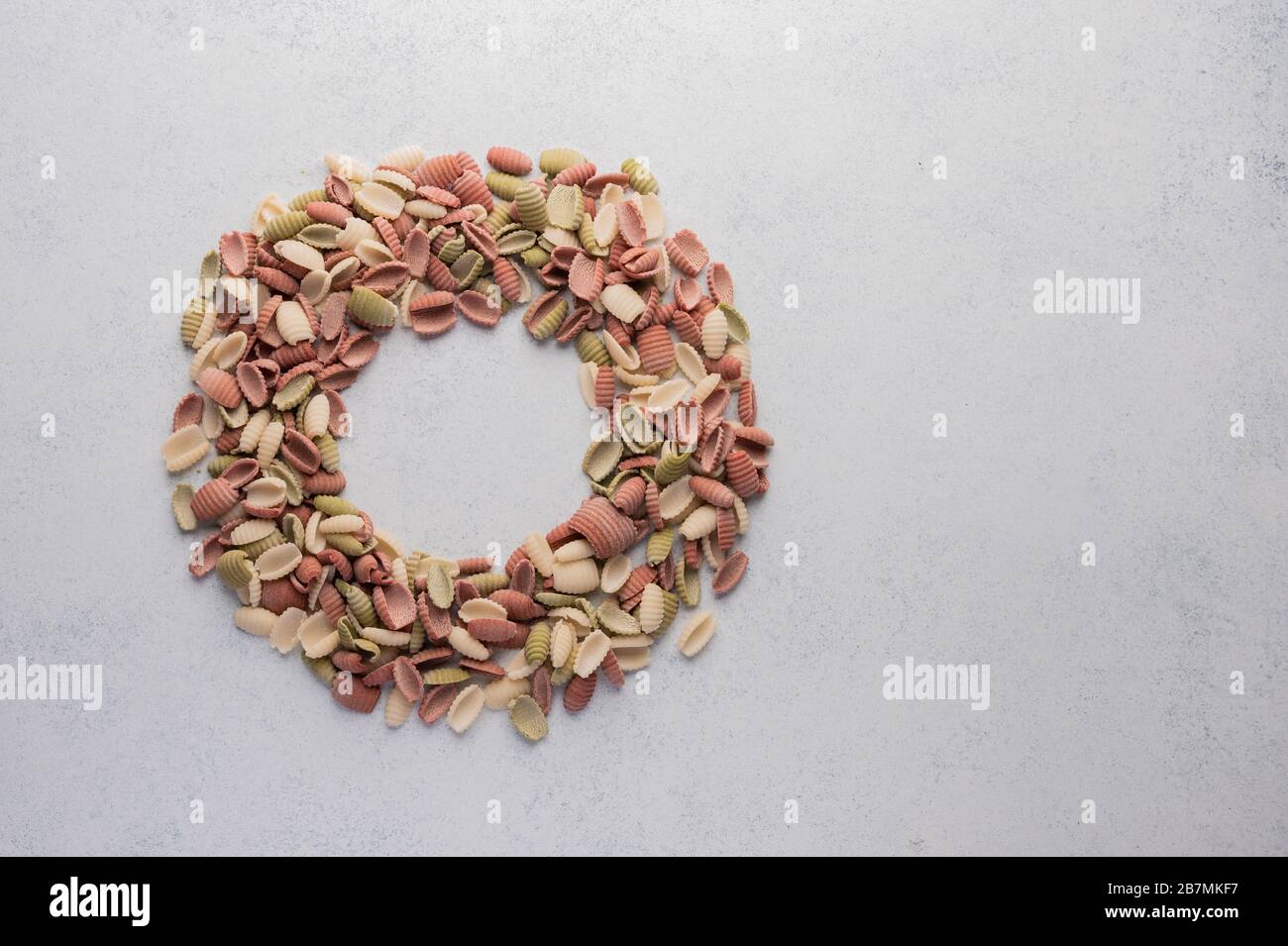 Multi-colored pasta shells in the shape of a circle with space in the ...