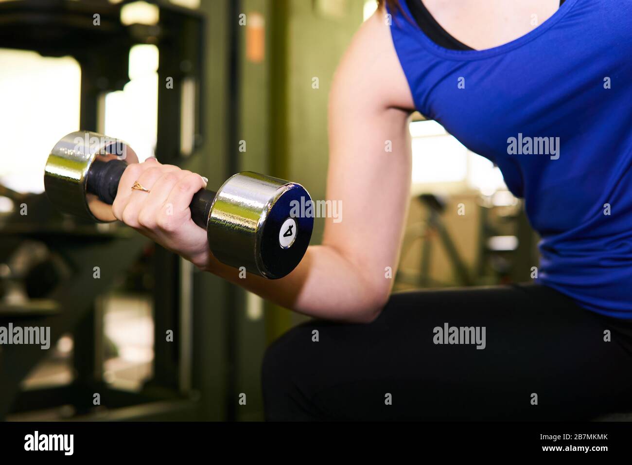 hand of a woman performing dumbbell exercise for biceps at the gym ...