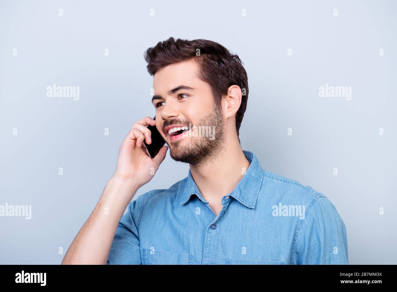 Excited young handsome boy is talking on his smartphone and smiling. He ...