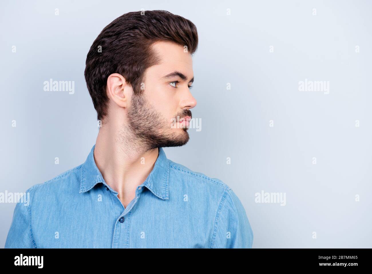 Close up portrait of serious young man looking at his left. He is ...