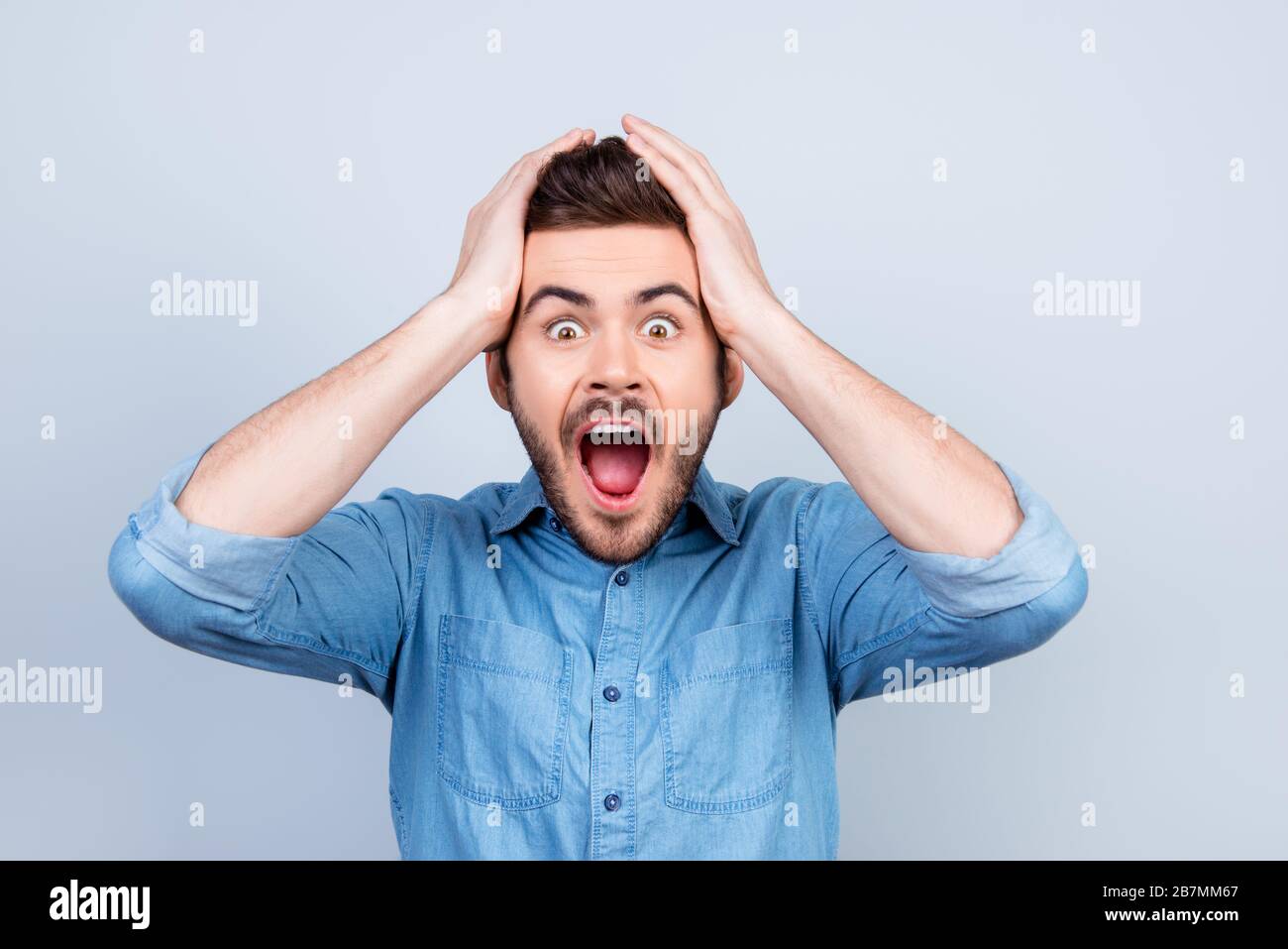 Omg! No way! Very shocked young man is holding his head with bith hands ...