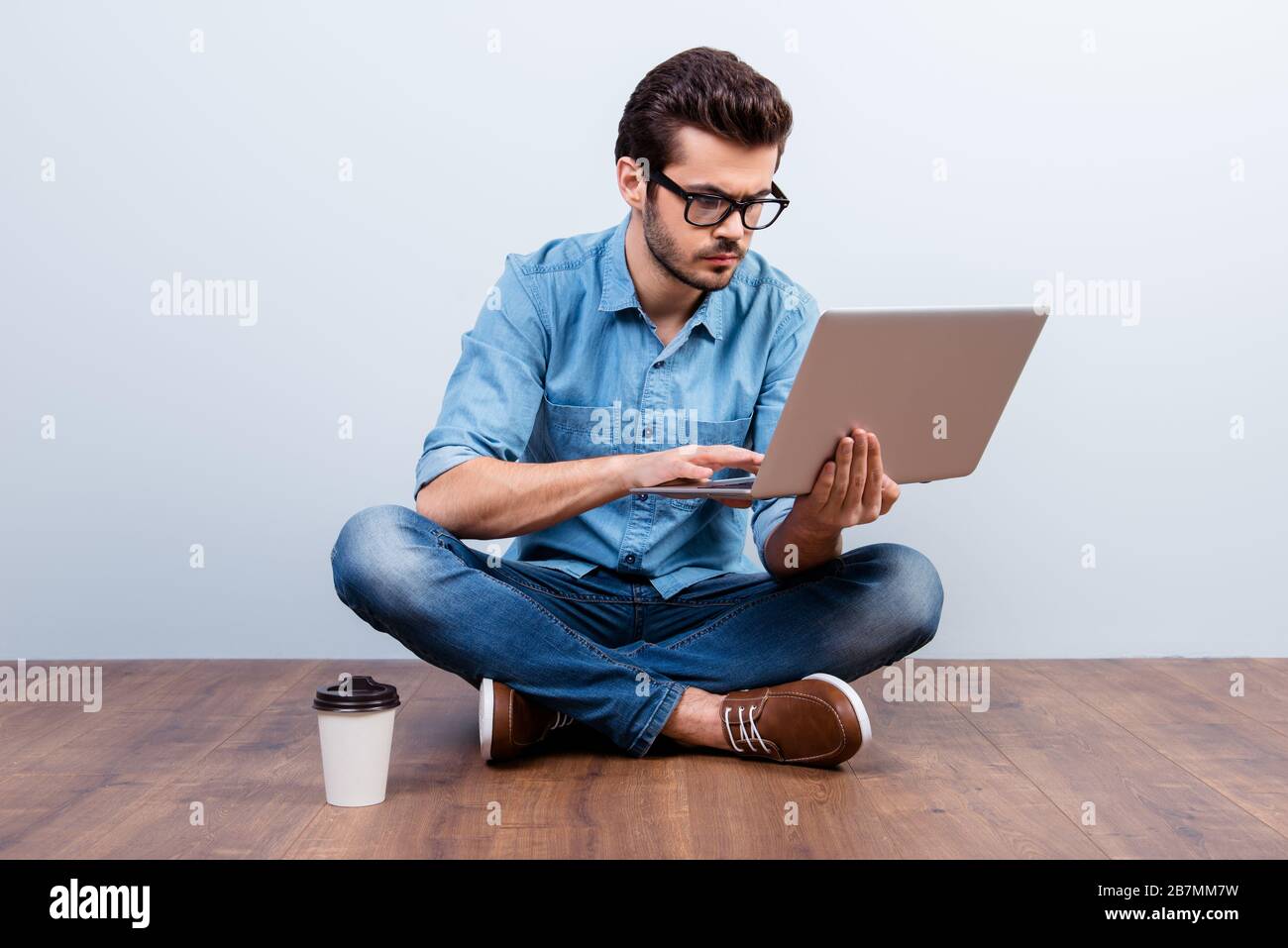 Portrait of concentrated young serious man typing on his laptop ...