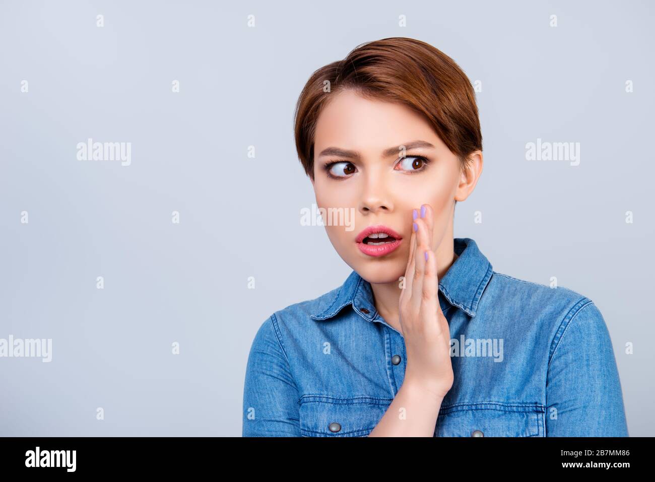 Young beautiful red hair girl is telling someone a secret and looks ...