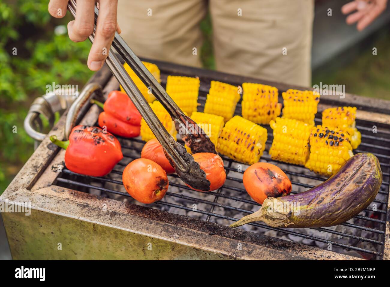 Man with tongs cooking on a back yard barbecue Stock Photo - Alamy