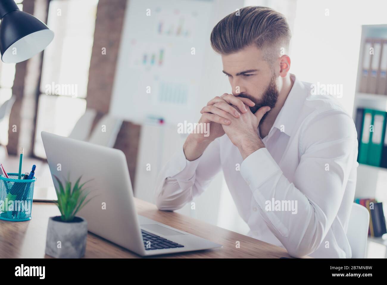 Young stylish worker at office working with computer and thinking how ...