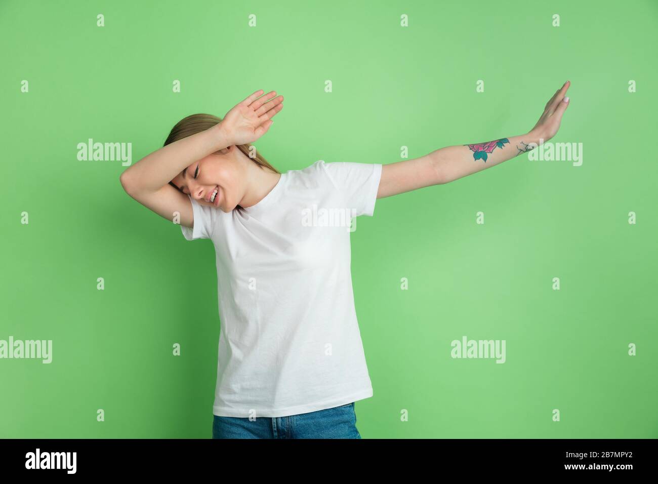 Winner's dab, dabbing. Caucasian young woman's portrait on green studio ...