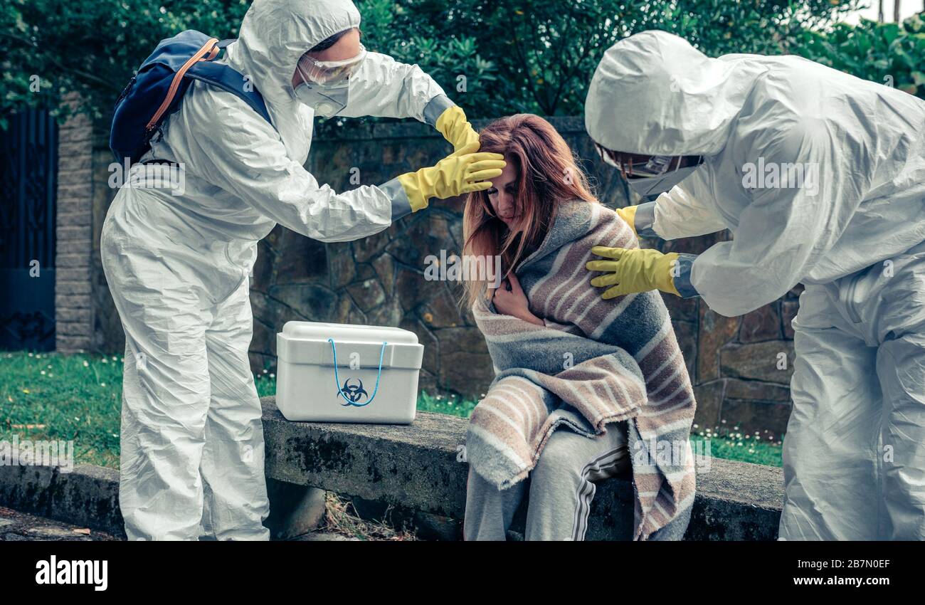 Doctors in protection suits caring for a woman Stock Photo - Alamy