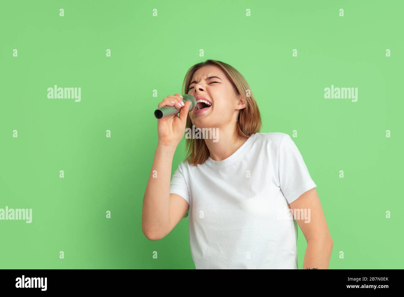 Singing with speaker. Caucasian young woman's portrait isolated on ...