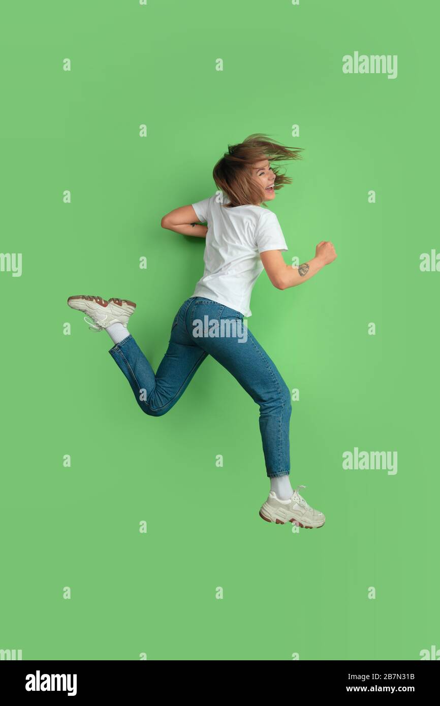 Running, laughting in jump. Caucasian young woman's portrait isolated ...