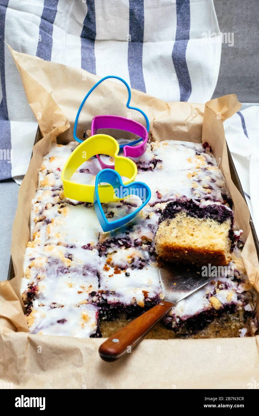 Blueberry cake on the baking tray with hearts and blade for cake. The ...
