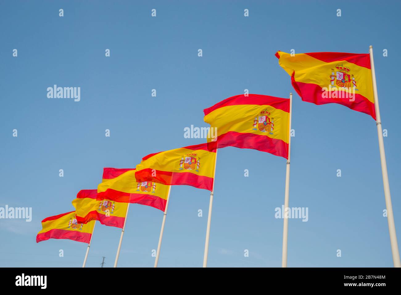 Spanish flags waving against blue sky Stock Photo - Alamy