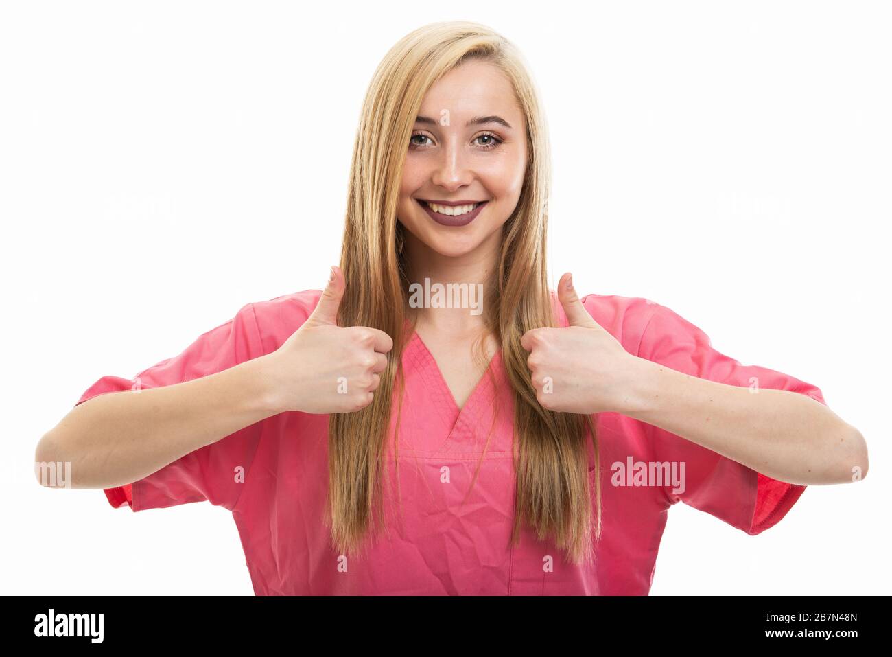 Portrait of cute young female nurse wearing scrubs showing double like ...
