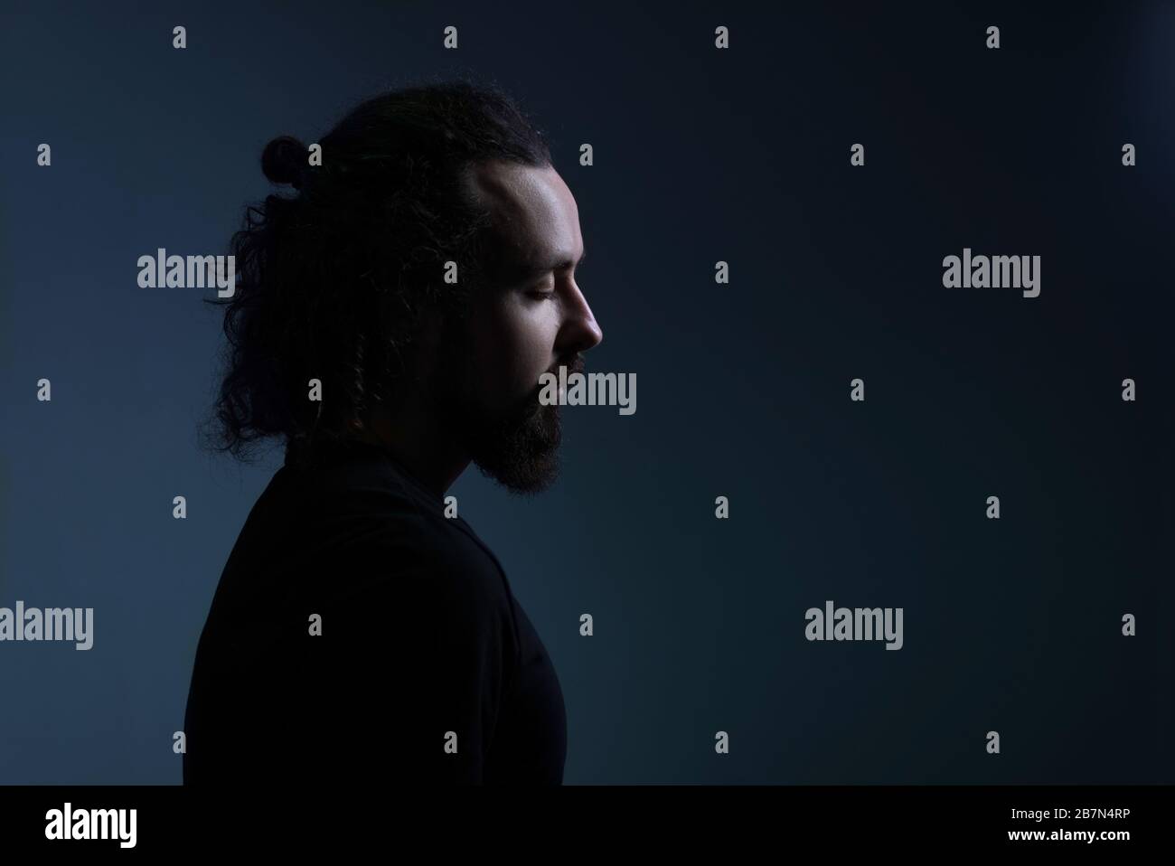studio dramatic profile portrait of a young bearded guy of thirty years ...