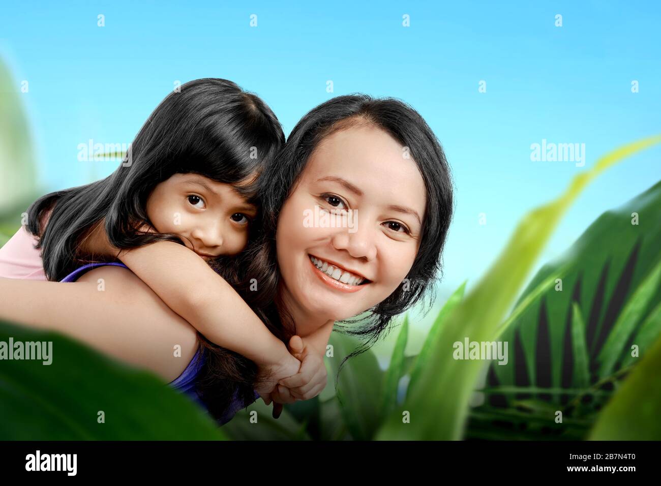 Asian mother carrying her little girl on her back. Mothers day concept ... Asian mother carrying her little girl on her back. Mothers day concept ...
