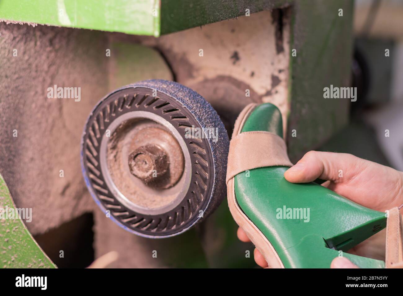 Shoemaker processes women's shoes on emery machine, shoemaking concept ...