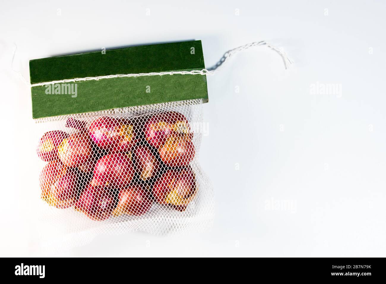 Red onions in mesh bag and some on floor isolated on white background ...