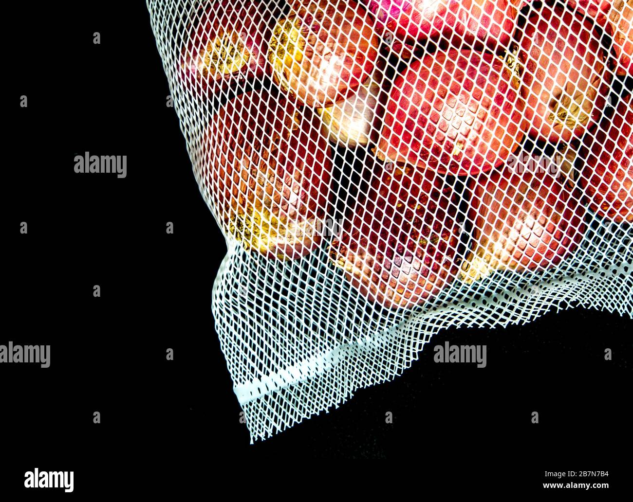 Red onions in mesh bag and some on floor isolated on black background ...